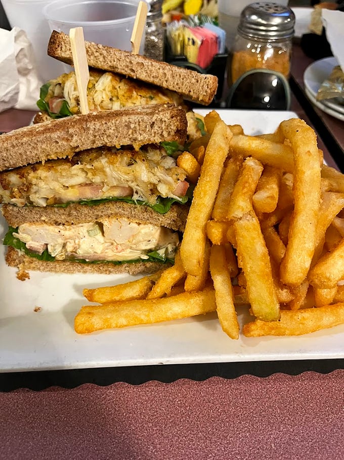 A sandwich that belongs in the Seafood Hall of Fame – golden shrimp salad piled high between toasted bread with crispy fries standing guard.