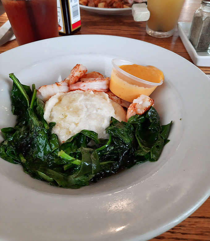 Shrimp nestled on a bed of vibrant greens with a perfectly poached egg—seafood breakfast that doesn't require an ocean view to be magnificent.