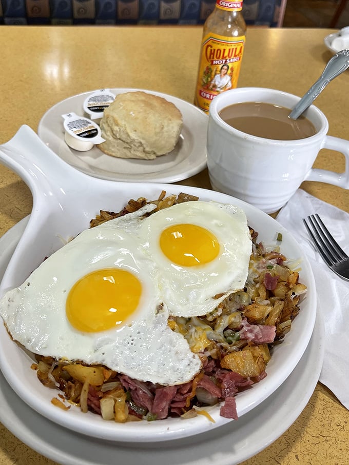 Two sunny-side-up eggs crown a mountain of home fries and ham – breakfast architecture that would make Frank Lloyd Wright proud.