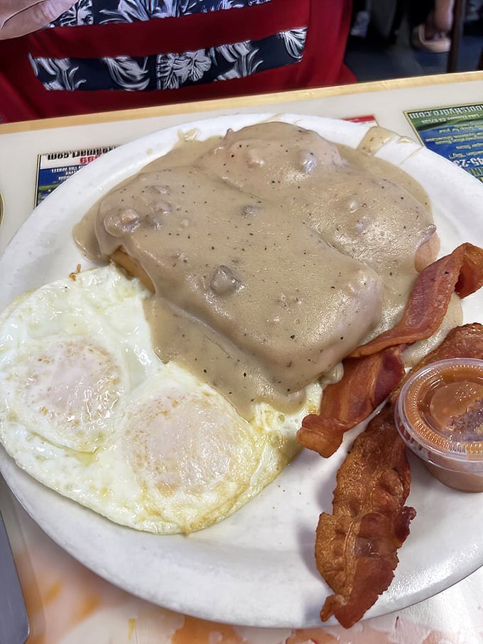 This is what Southern comfort looks like on a plate – biscuits drowning in gravy, eggs, and bacon perfection.