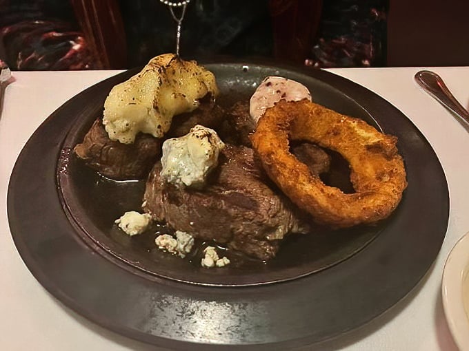 Steak perfection doesn't need elaborate presentation—just a properly cooked cut, blue cheese crumbles, and that onion ring crown fit for beef royalty.
