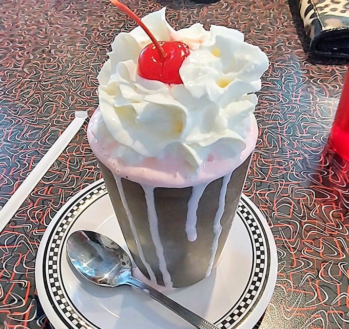 This isn't just a milkshake—it's architecture in a glass, with whipped cream mountains and that perfect cherry summit waiting to be conquered.