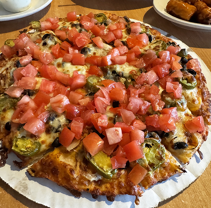 Fresh diced tomatoes cascade over melted cheese and jalapeños like confetti at a flavor parade. This pizza doesn't just cross borders—it demolishes them.