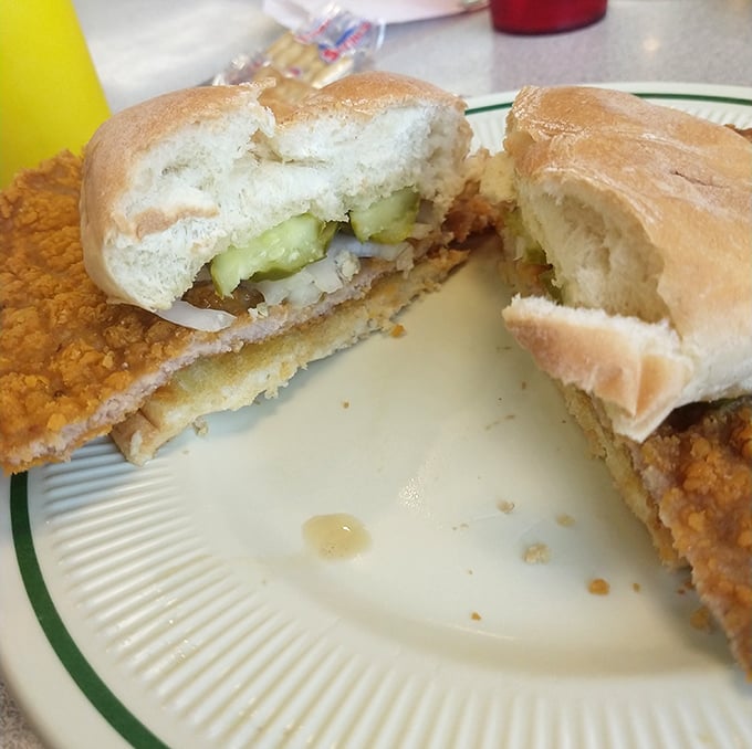 The legendary tenderloin sandwich in all its glory—golden-brown, crispy exterior extending well beyond its bun boundaries. This is sandwich architecture at its finest.