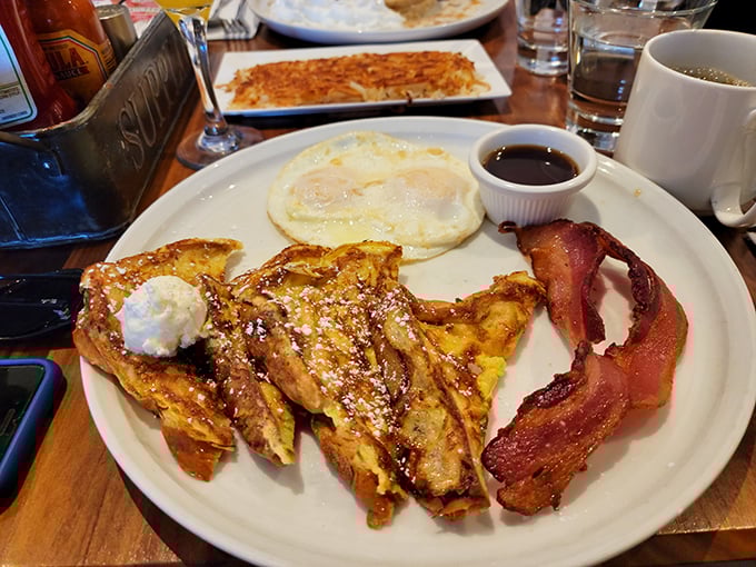 The legendary French toast combo—golden, crispy exterior giving way to custardy perfection, with eggs and bacon playing perfect supporting roles.
