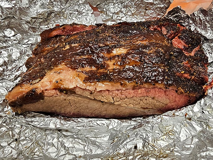 Behold the brisket – a glistening monument to patience where smoke and time transform tough meat into something so tender it practically whispers your name.
