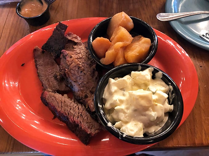 Behold the holy trinity of barbecue perfection: fork-tender brisket with that coveted smoke ring, alongside creamy mac and cheese and cinnamon apples.
