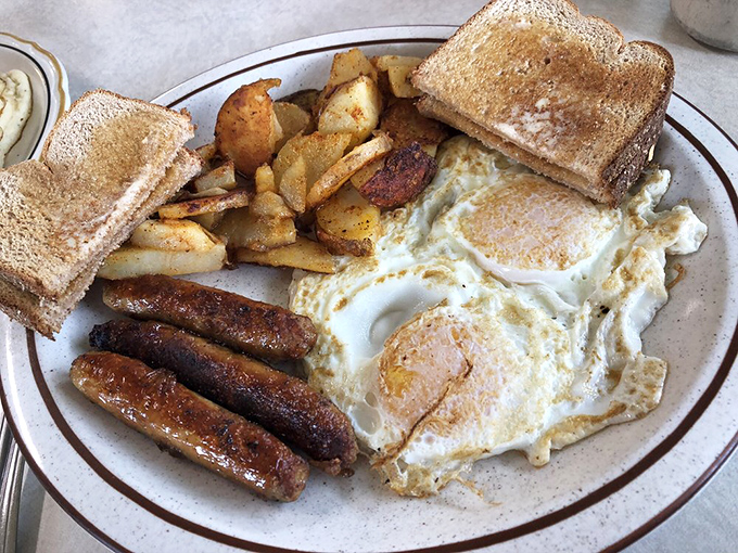 Breakfast perfection on a plate! Sunny-side eggs, golden home fries, and sausages that snap when you cut them—this is how mornings were meant to begin.