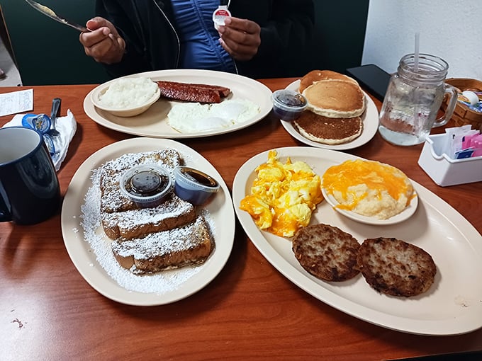 Breakfast spread that would make Ron Swanson weep with joy. French toast dusted with powdered sugar alongside eggs and sausage patties—morning nirvana.