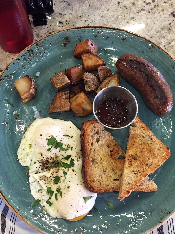 Breakfast perfection on a turquoise plate – the sunny egg, perfectly toasted bread, and those potatoes looking like they've achieved their highest purpose in life.