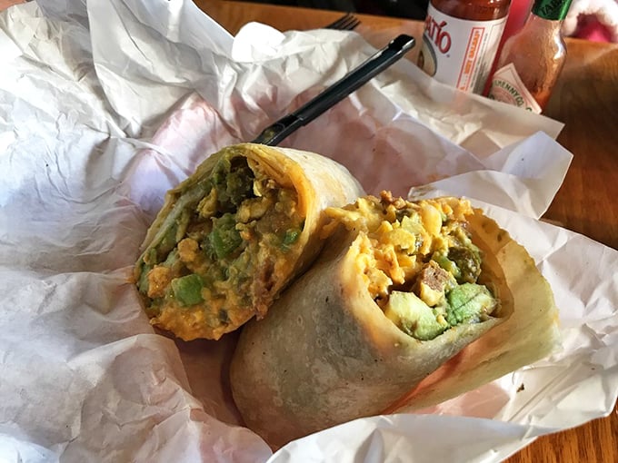 Behold the breakfast burrito in its natural habitat—a perfect marriage of eggs, avocado, and potatoes wrapped in a tortilla that somehow defies the laws of physics.