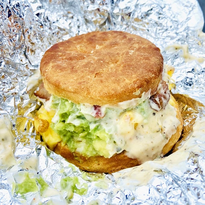 Behold "The Special"—a glorious monument to morning indulgence where avocado, eggs, and aioli create a breakfast symphony in biscuit form.