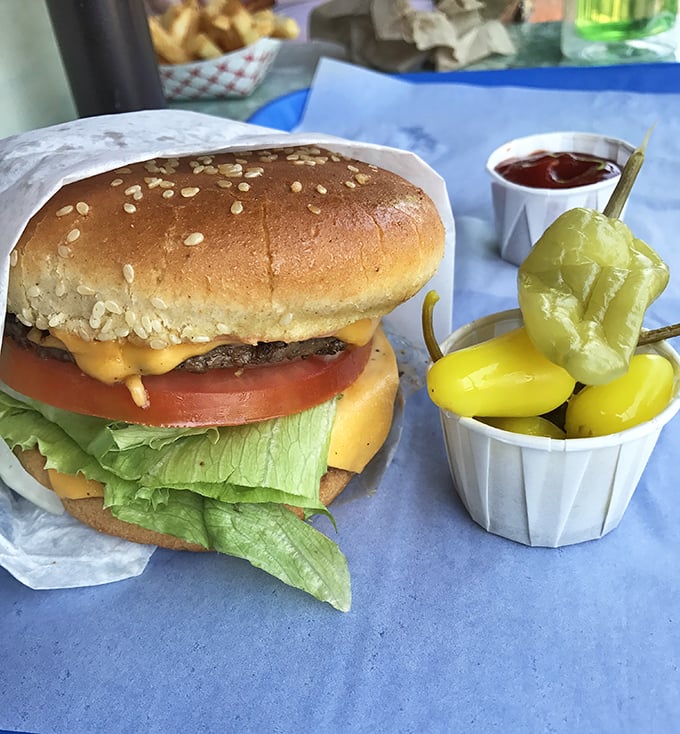 Behold the star of the show: a perfectly constructed cheeseburger with all the right accessories. Those pickles aren't just garnish—they're supporting actors deserving their own award.