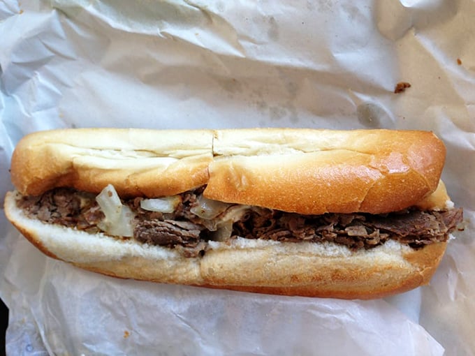 The cheesesteak in its natural habitat—perfectly nestled in a fresh roll with onions playing their supporting role to perfection.