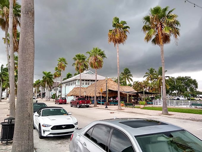 Stormy skies create dramatic backdrops for Fort Pierce's charming streetscape, where palm trees stand sentinel over tiki-roofed escapes from reality.