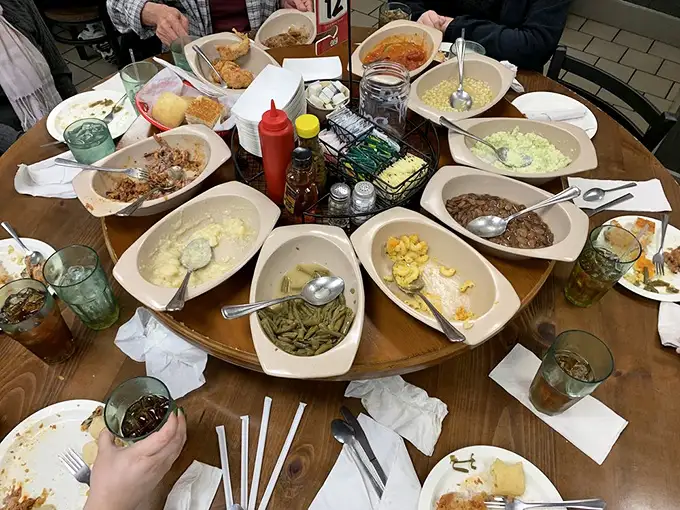 The lazy Susan in its natural habitat—a circular United Nations of Southern sides where diplomatic relations involve passing the mac and cheese without taking the last scoop.