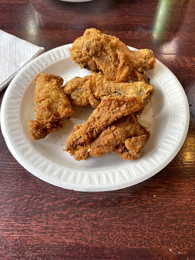 Golden-brown perfection on a paper plate. This isn't just fried chicken; it's edible nostalgia that makes your taste buds do a happy dance.