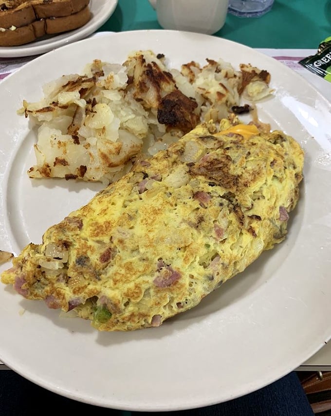 This isn't just an omelet—it's a masterpiece of morning engineering, packed with savory bits of ham and veggies alongside perfectly crisped potatoes.