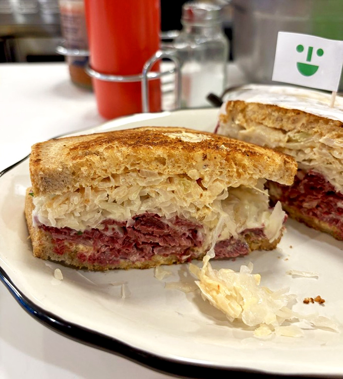 The legendary Reuben in all its glory—perfectly stacked corned beef, tangy sauerkraut, and melted Swiss creating a symphony of flavors between toasted bread.