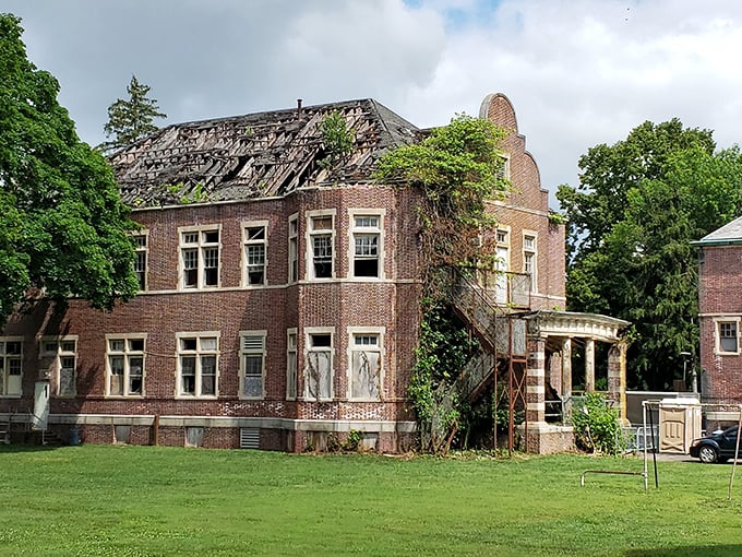 Nature slowly reclaims what humans abandoned, with vines creeping up the brick façade like fingers trying to pull the building back into the earth.