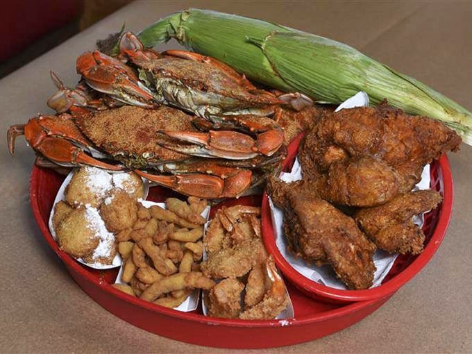 Not a fancy plating in sight, just a glorious red basket of seasoned blue crabs, golden hush puppies, and fried chicken that means business.