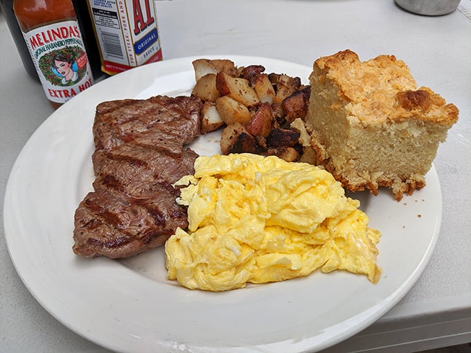 This is what breakfast commitment looks like – a perfectly seared steak, fluffy scrambled eggs, crispy potatoes, and cornbread that would make your grandma jealous.