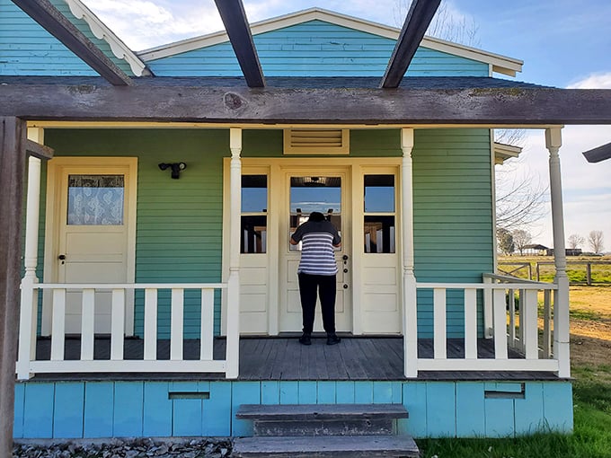 A visitor peers into the past through the turquoise-framed doorway, where history isn't just preserved—it's waiting to be experienced firsthand.