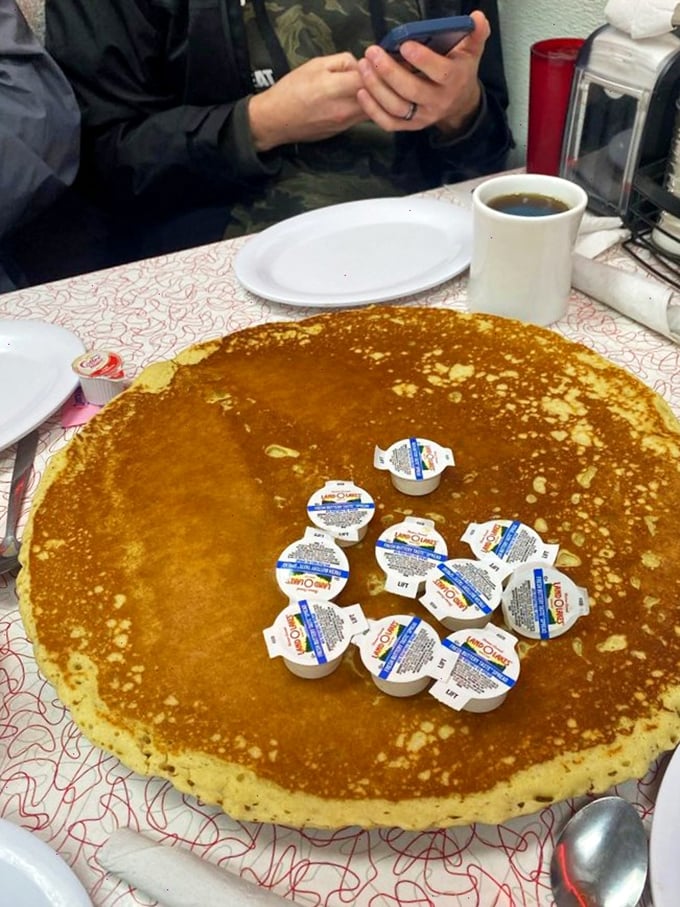 The legendary 16-inch pancake doesn't just feed you—it dares you. Those cream containers aren't garnish; they're ammunition for the sweet battle ahead.