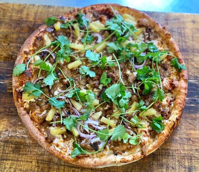 Fresh cilantro and pineapple dance atop this pizza like they're celebrating the marriage of sweet and savory – a fiesta on flatbread.