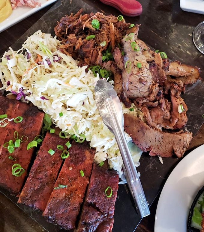 The BBQ platter arrives like a carnivore's dream team—ribs, brisket, and pulled pork flanked by cooling coleslaw, ready for your undivided attention.