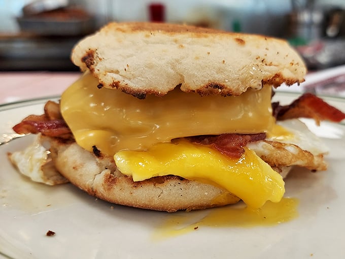 This breakfast sandwich isn't playing around—melted cheese cascades over bacon and egg on an English muffin like a sunrise worth waking up for.