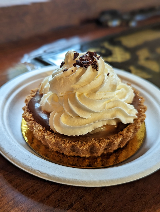 The Banoffee tart arrives like a cloud of cream atop chocolate decadence—proof that heaven exists and it's served on a gold-rimmed plate.