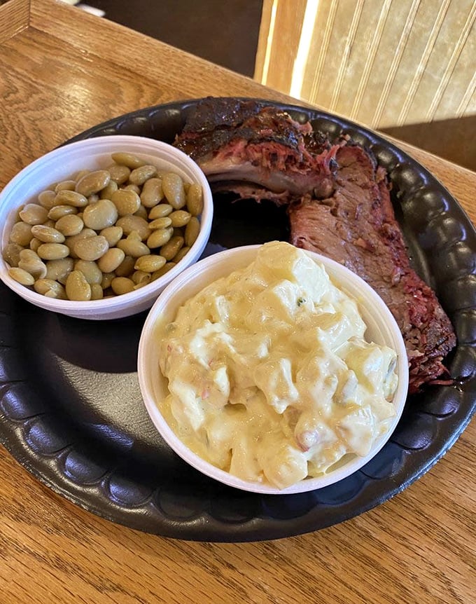 This brisket has more smoke rings than a retirement party at a cigar factory, perfectly paired with lima beans and potato salad.