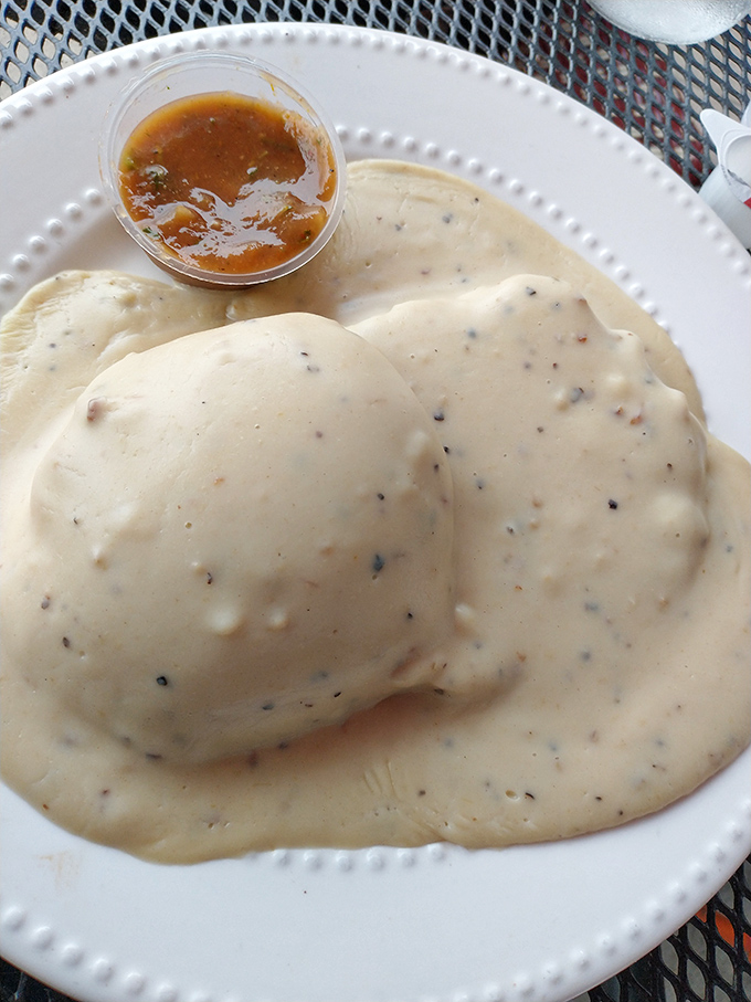 Biscuits and gravy so comforting they should come with a pillow. That little cup of hot sauce stands ready for those brave enough to disrupt breakfast perfection.