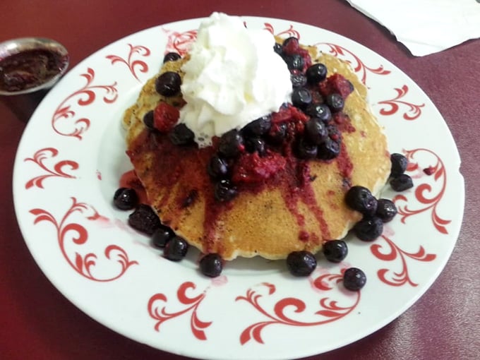 These berry-crowned pancakes aren't just breakfast—they're edible joy. The whipped cream melting into warm blueberry syrup creates morning magic on a plate.