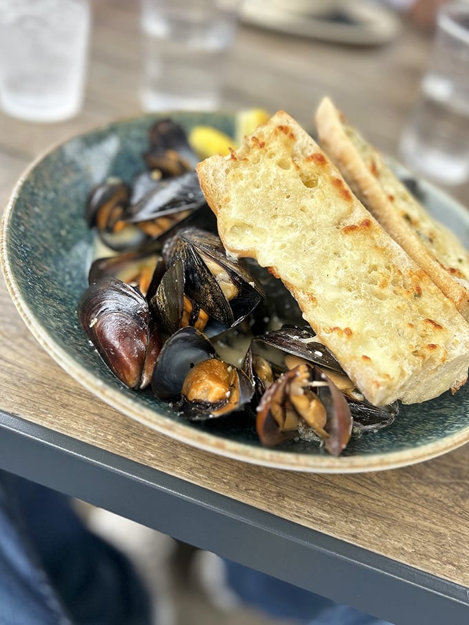 These mussels aren't just seafood—they're little navy-blue vessels of joy, swimming in a broth you'll want to drink straight from the bowl.