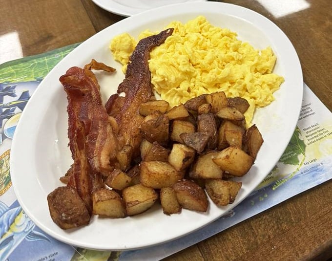 The breakfast trinity – crispy bacon, fluffy scrambled eggs, and home fries that would make your grandmother nod in silent approval.