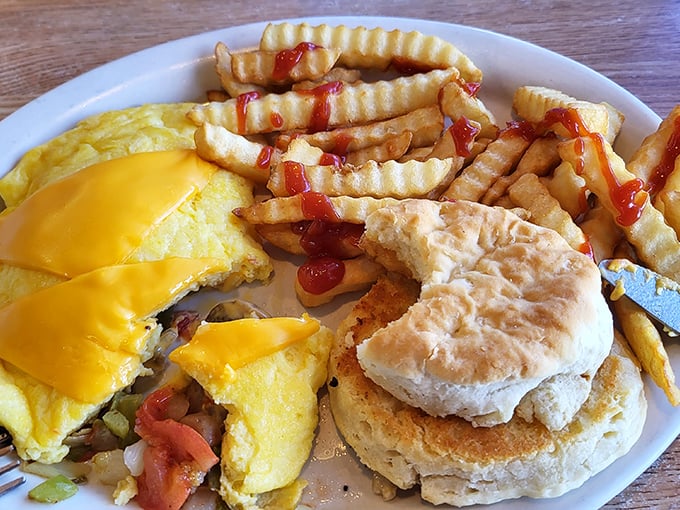 Western omelet, crinkle-cut fries, and a fluffy biscuit—the holy trinity of diner breakfast. That melted cheese blanket is performing acts of culinary kindness.