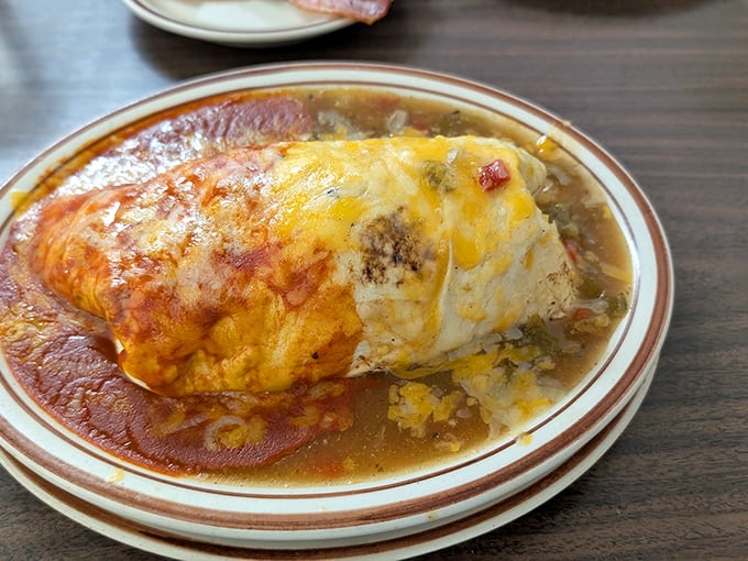 The breakfast burrito at Vic's doesn't just arrive at your table – it makes an entrance, dressed in red chile and melted cheese.