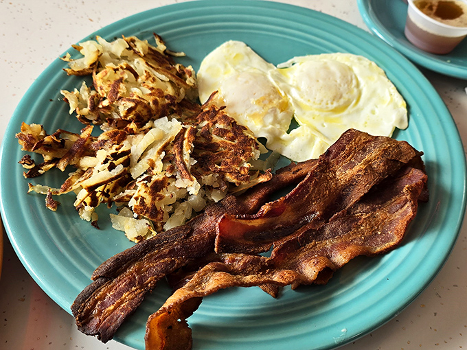 Breakfast perfection isn't complicated: crispy bacon, golden hash browns, and eggs with yolks that pop like tiny suns on your plate.