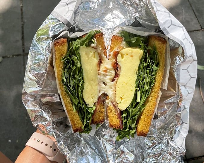 This isn't just a sandwich—it's architecture. Layers of fresh ingredients nestled between perfectly toasted bread, with greens adding both color and conscience.