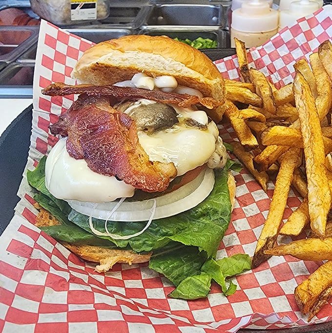 This isn't just a burger, it's architecture – layers of bacon, cheese, and fresh vegetables stacked with structural integrity that would impress Frank Lloyd Wright.
