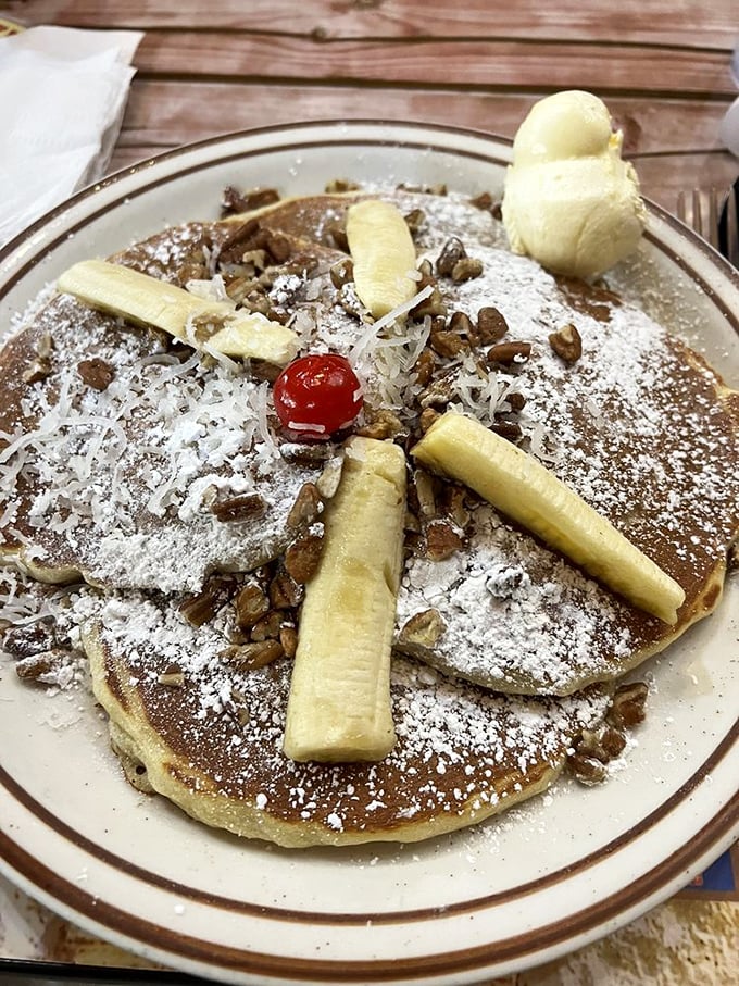 A pancake vacation for your taste buds—banana slices and pecans arranged like sunshine rays on a golden-brown horizon.