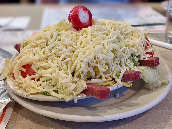 The Italian salad arrives like a snow-capped mountain of cheese, with radishes and pepperoncini playing hide-and-seek beneath—a prelude that could easily be the main event.
