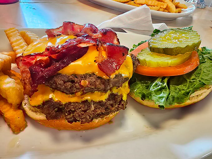 The bacon cheeseburger arrives like a skyscraper of satisfaction—structural engineering that prioritizes flavor over the laws of gravity.
