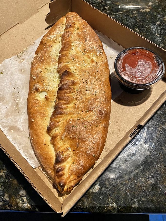 The stromboli—a magnificent dough canoe filled with treasure—sits ready for dipping in that little cup of marinara magic.