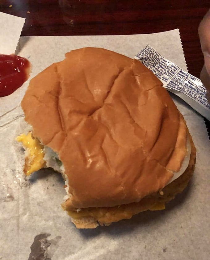 The chicken sandwich in its natural habitat – wax paper, melty cheese, and a bite already missing because waiting for photos was simply impossible.