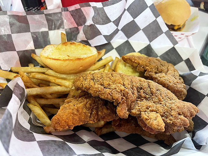 Golden-brown chicken tenders that crunch louder than your dad's favorite recliner, nestled beside fries that deserve their own fan club.
