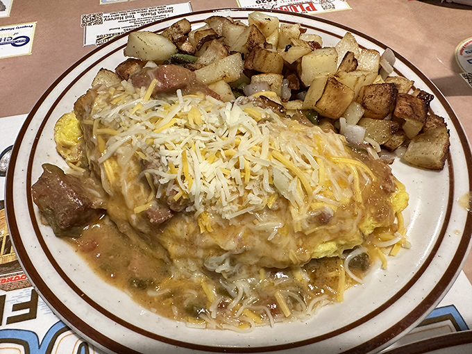 This isn't just an omelet—it's a cheese-covered monument to morning indulgence, with those perfectly crispy home fries playing the essential supporting role.