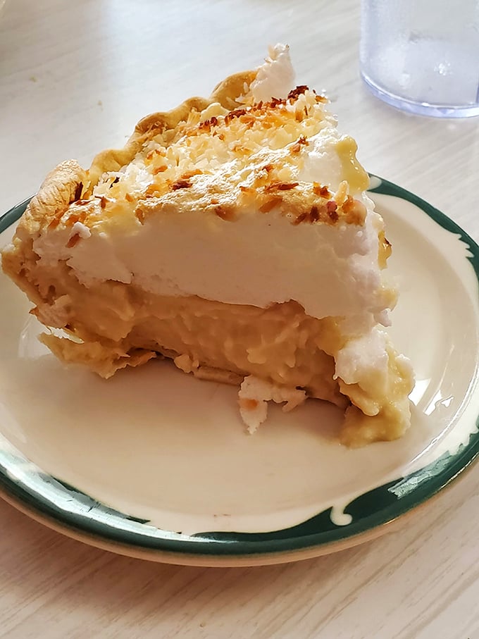 Behold the coconut cream pie in all its towering glory—a cloud-like meringue masterpiece that defies both gravity and willpower.